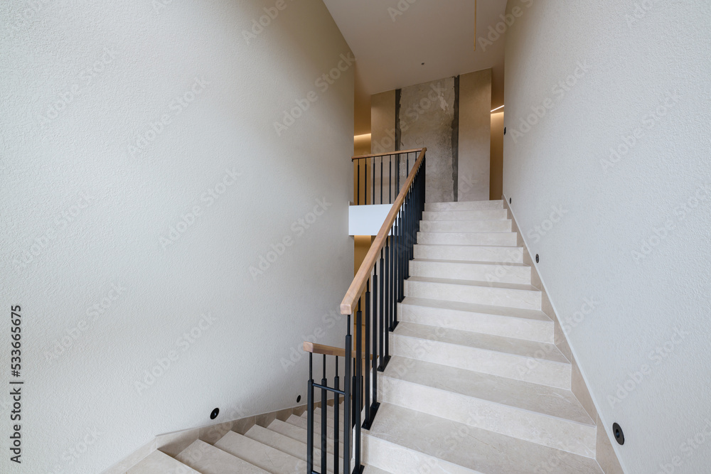 stairs made of tiles in a new house. metal black railing with wooden ...