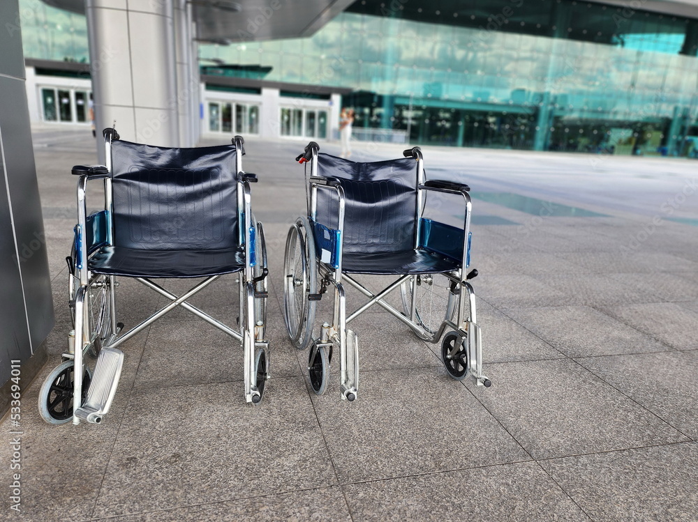 Two wheelchairs are lined up in front of a hospital or shopping mall ...