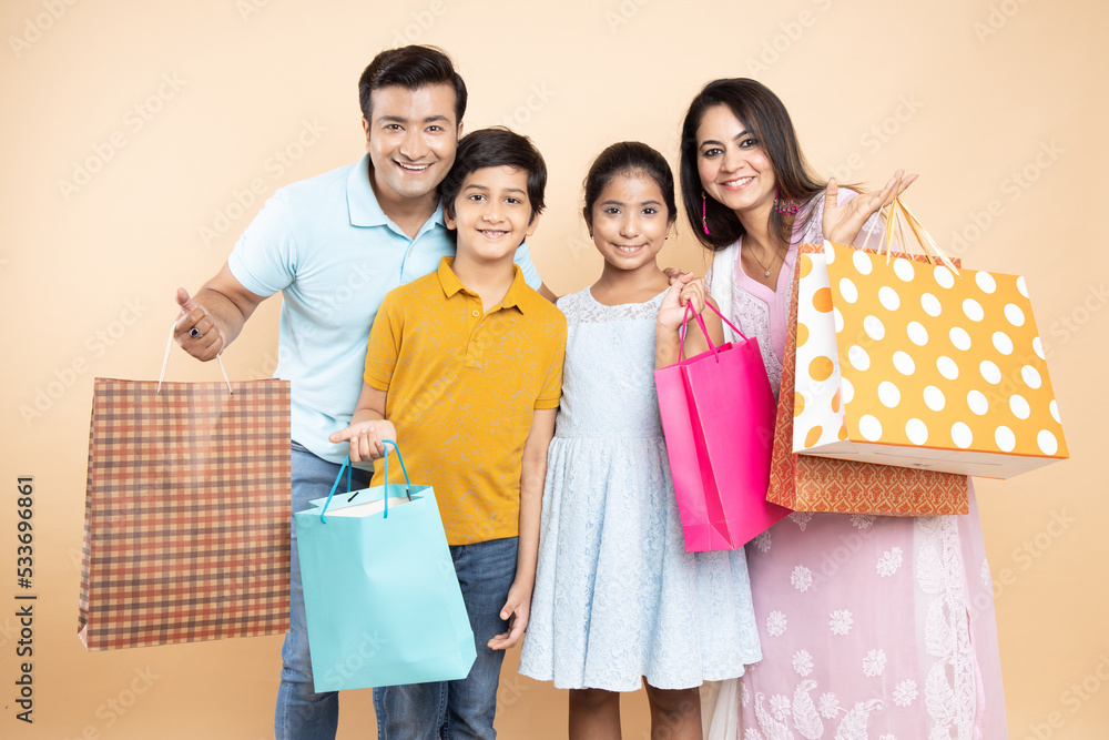 Portrait of happy indian family wearing casual cloths holding shopping bags and celebration ...
