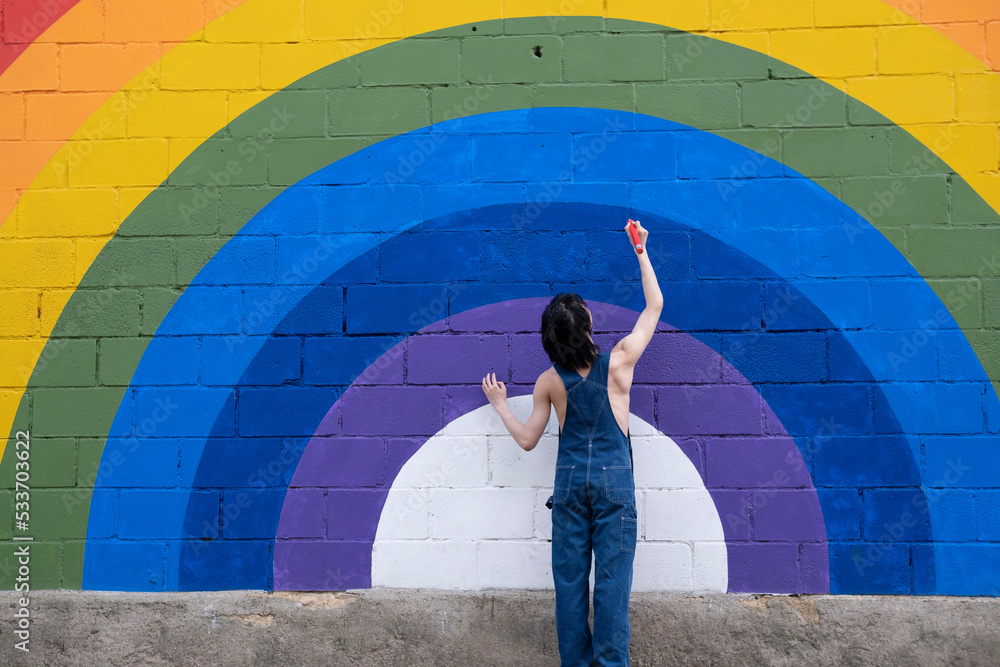 Young man drawing with pencil on rainbow mural Stock Photo | Adobe Stock
