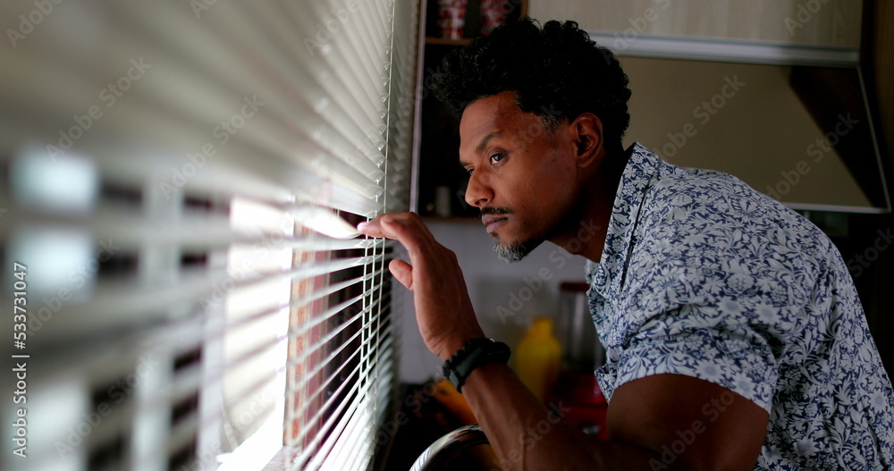 Suspicious man looking through window blinds Stock Photo | Adobe Stock