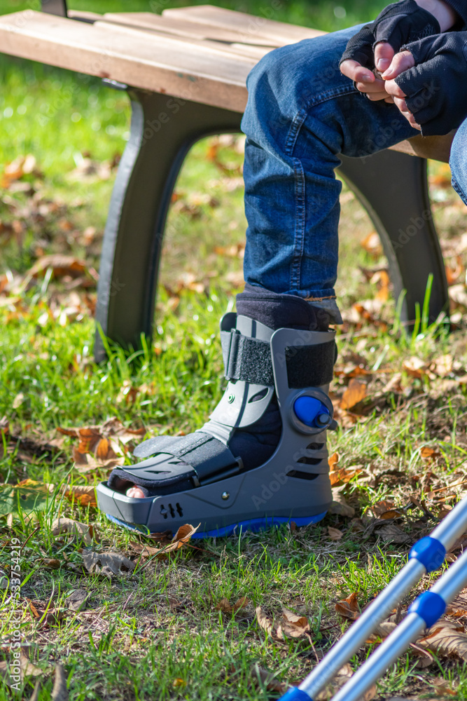 Boy with broken foot and orthopedic shoe or walker after bone fracture ...