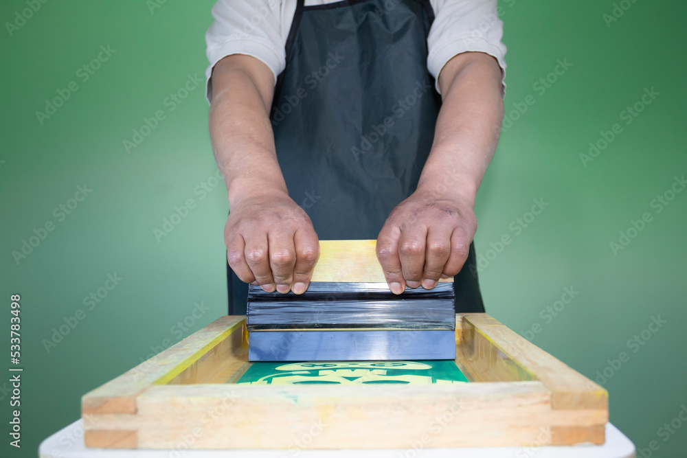 Foto de The hands of the man carry out the work of serigraphy, on the ...