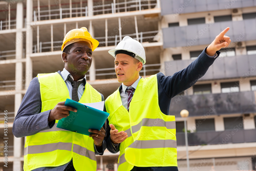 Young civil engineer discussing a construction plan with a colleague ...