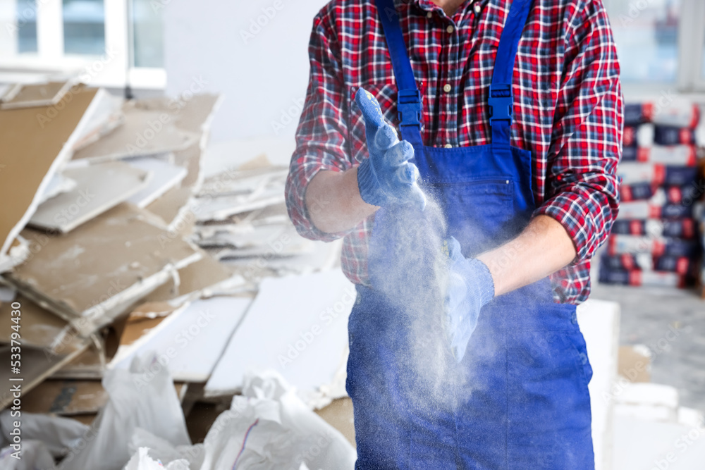Construction worker shaking off dust from hands in room prepared for ...