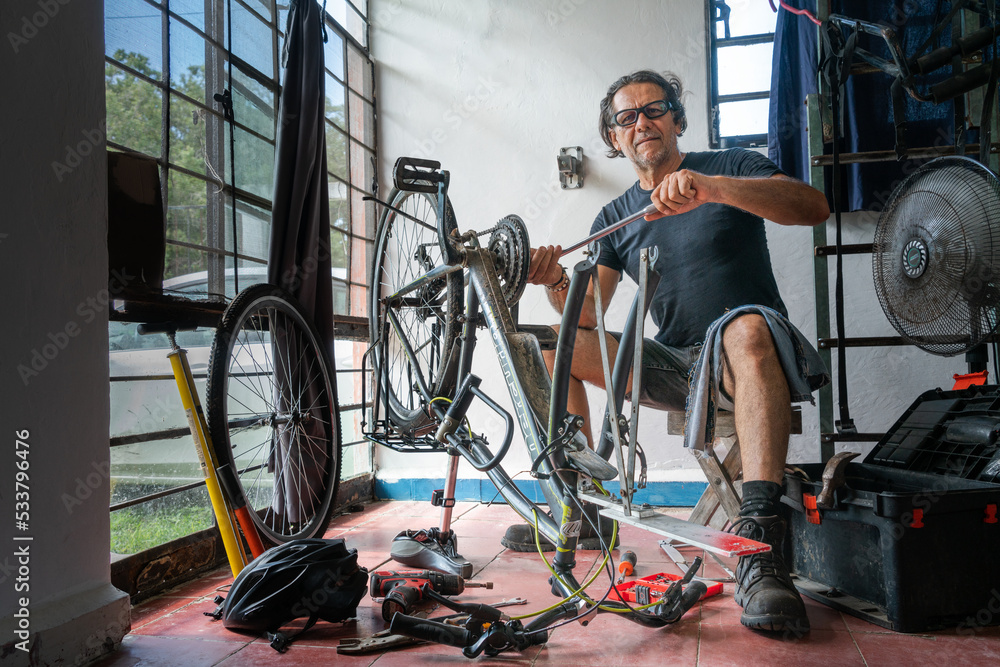 Hombre reparando una bicicleta en su casa Stock-Foto | Adobe Stock