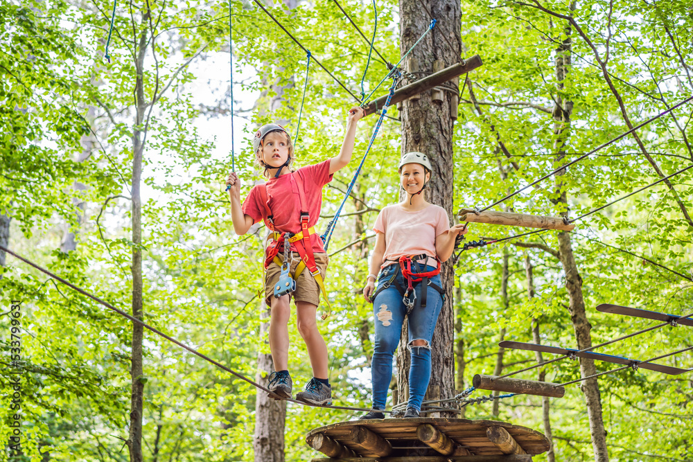 Mother and son climbing in extreme road trolley zipline in forest on ...