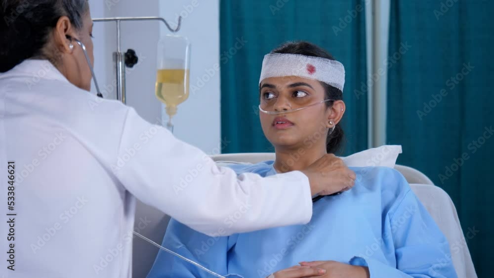 A middle-aged Indian lady doctor is using a stethoscope to check the ...
