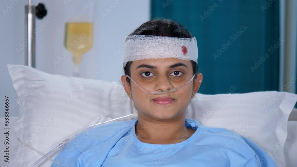 A young Indian woman with a bandage on her head is looking at the ...