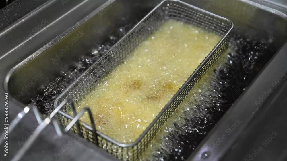 Frying the thin slices of potatoes in an automatic fryer, preparation ...