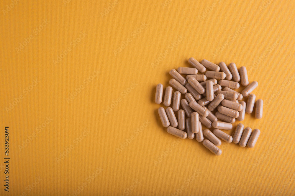 brown capsules with medicines on a yellow background Stock Photo ...