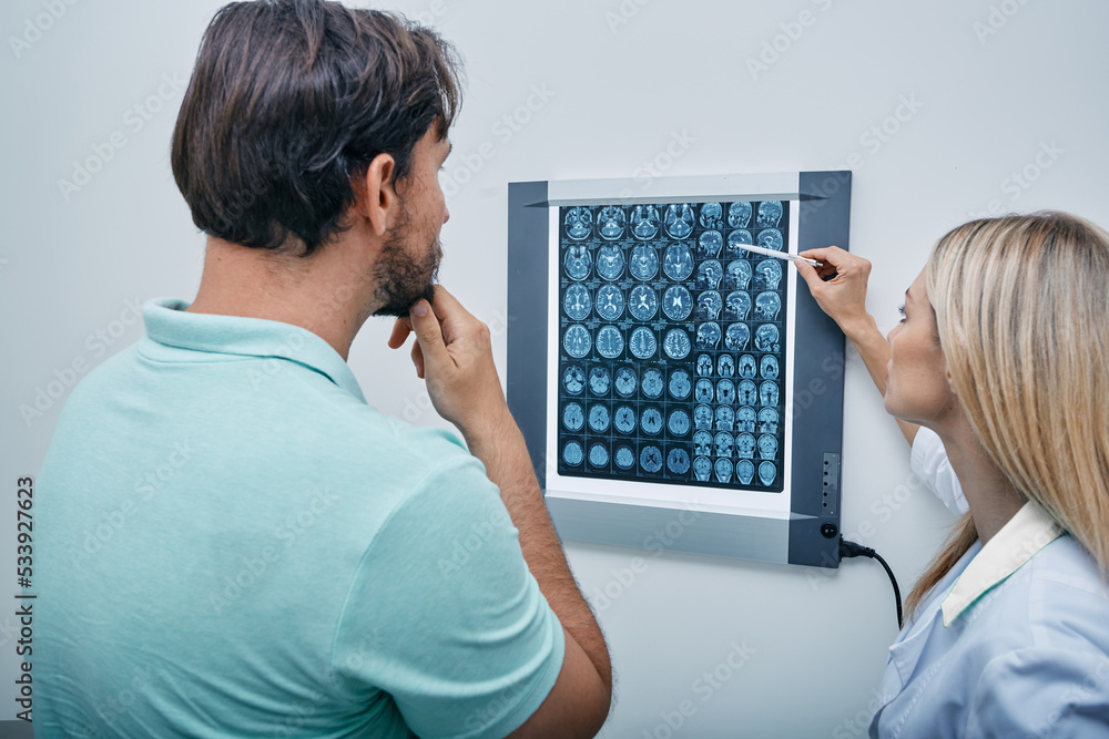Practicing doctor together with male patient watching MRI scan of brain ...