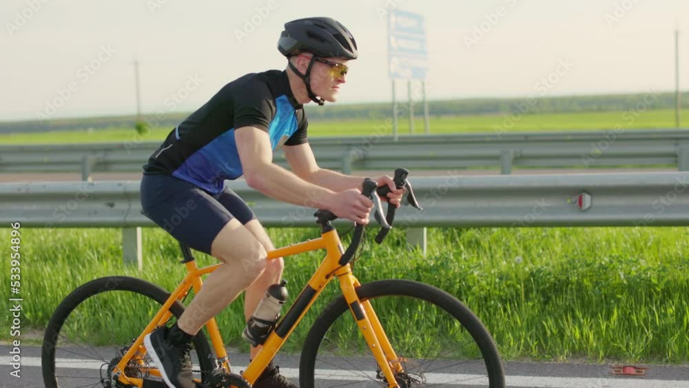 Active healthy man riding orange bike on open road with beautiful ...