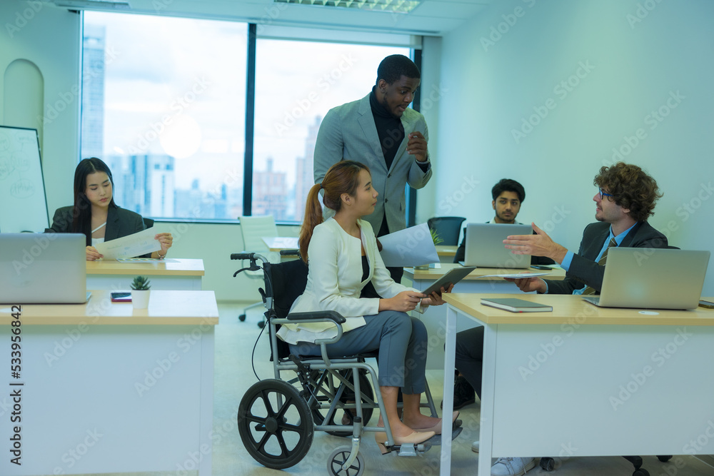 Foto de Asian woman who use the wheelchair working in office with ...