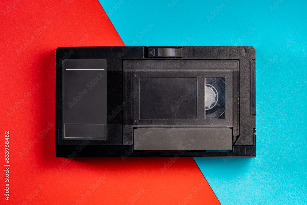 Black vintage VHS videotape cassette on red and blue background ...