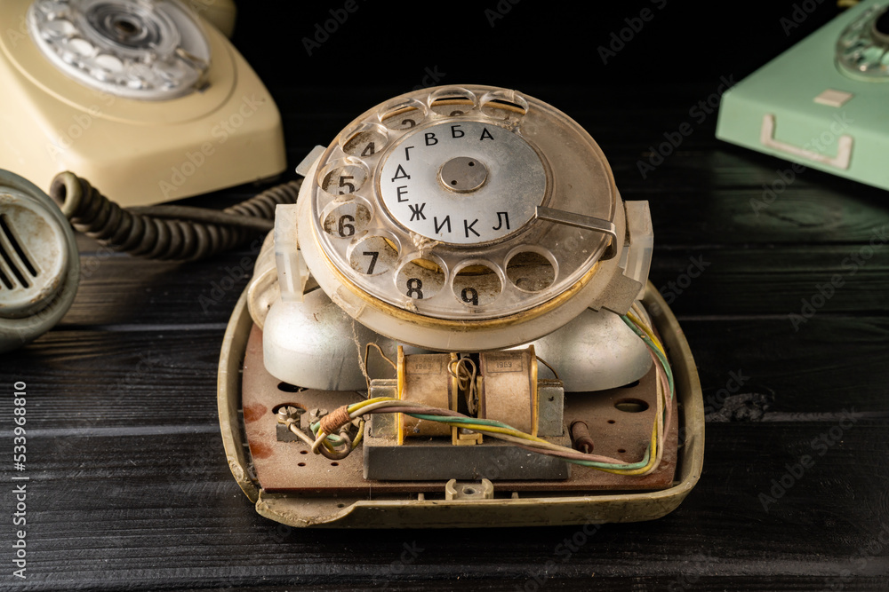 Old disassembled rotary telephone on a black wooden table. Internal ...