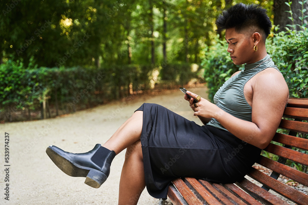 Filipino transgender woman using smartphone on bench Stock Photo ...