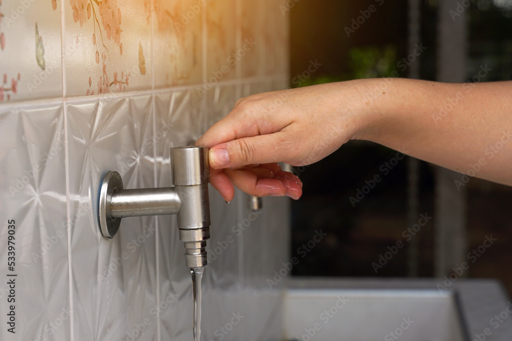 Asian woman's hand is turning off the water when she sees the faucet ...
