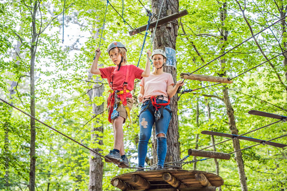Mother and son climbing in extreme road trolley zipline in forest on ...