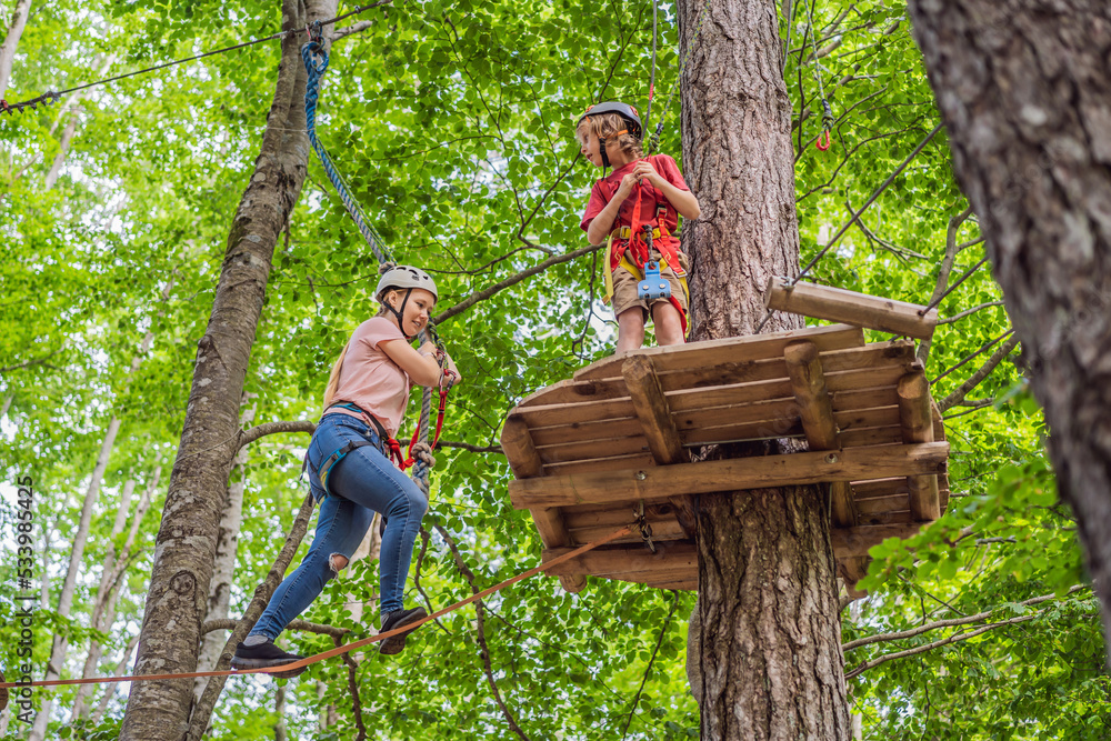Mother and son climbing in extreme road trolley zipline in forest on ...