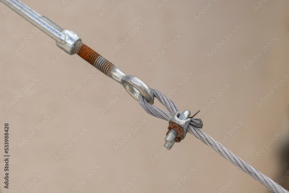 A turnbuckle with a metal cable holding building structures against a ...