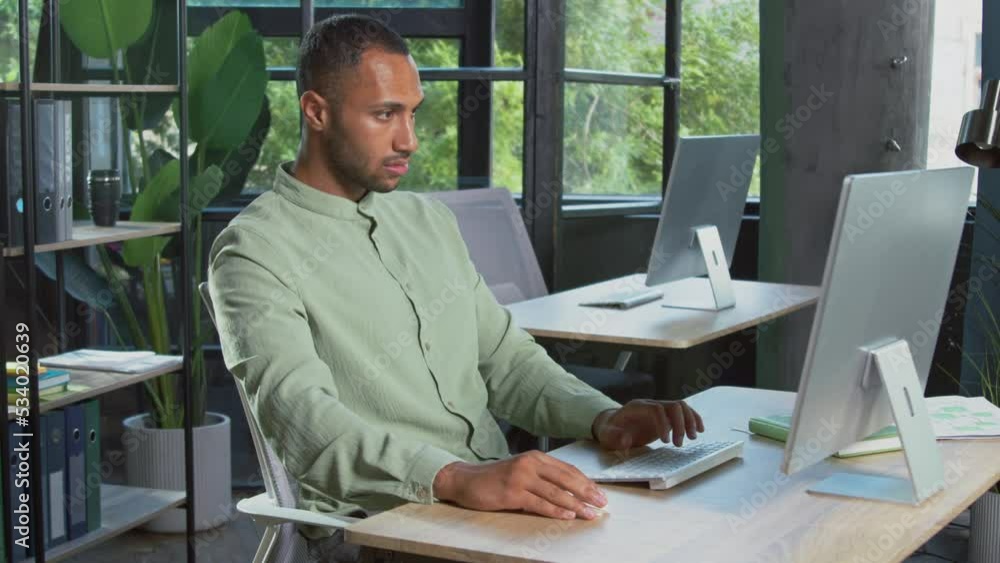 Shot of young attractive focused smart African man sitting at workplace ...