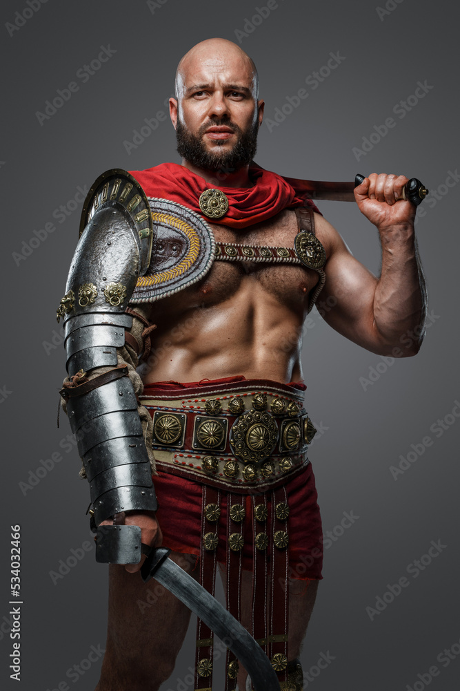 Portrait of ancient gladiator with bare torso posing with dual swords ...
