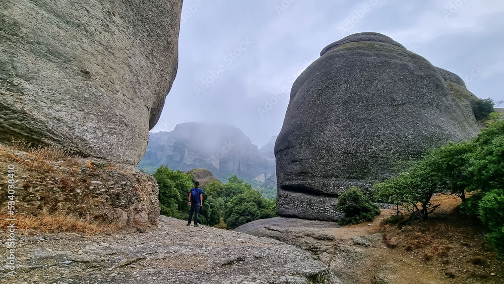 Active man with backpack standing under massive rock formation ...