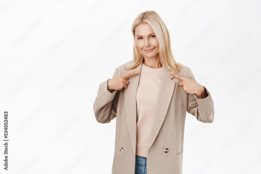 Smiling blond middle aged woman, mature lady in her 50s, pointing ...