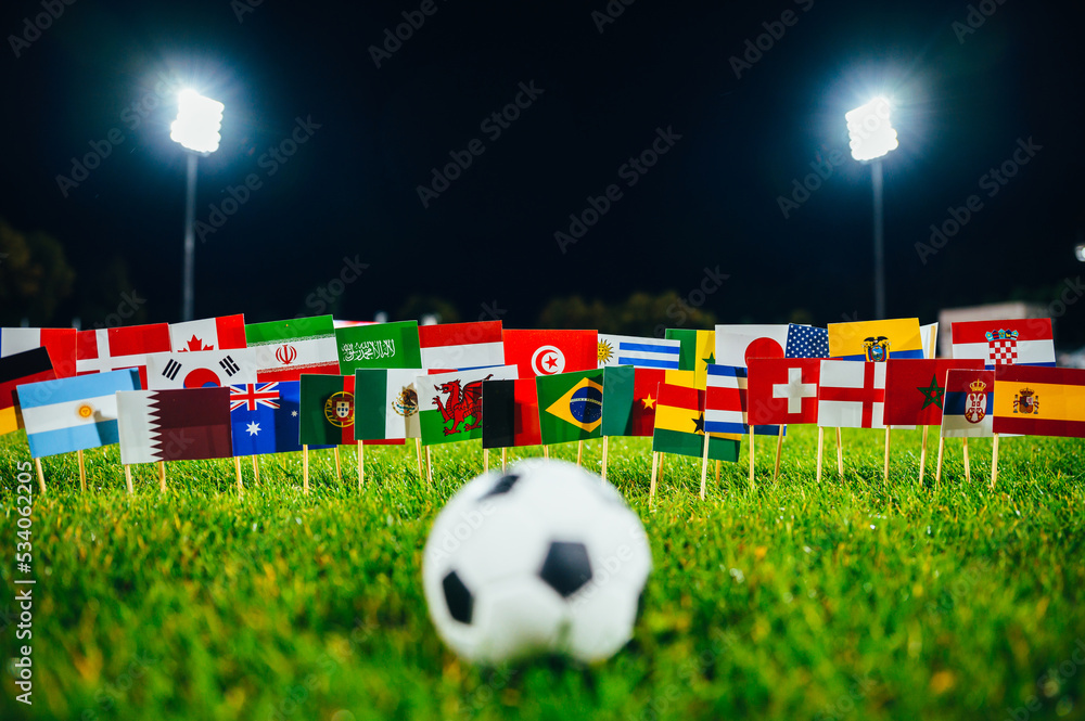 Football ball on green grass and all 32 national flags. Soccer game ...