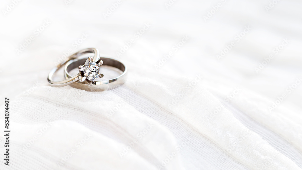 Pair of golden wedding rings on white textile background with copy ...