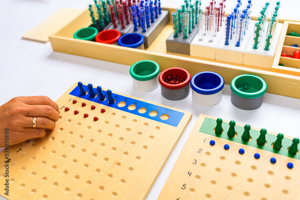 Detail of a montessori board division with the hand of a guide and ...