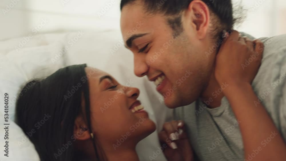 A couple in the bedroom love and kiss in bed, laying together. Laughing ...