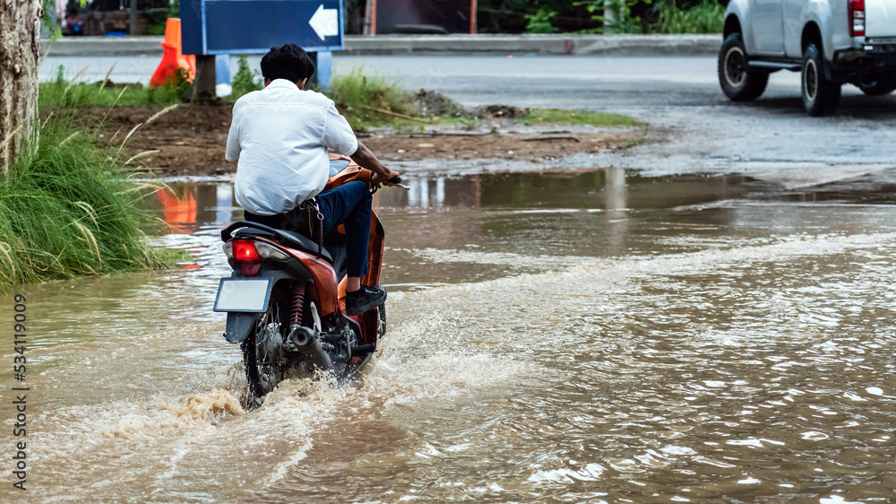 Man ride motorcycle passing through flooded road. Riding motorbike on ...