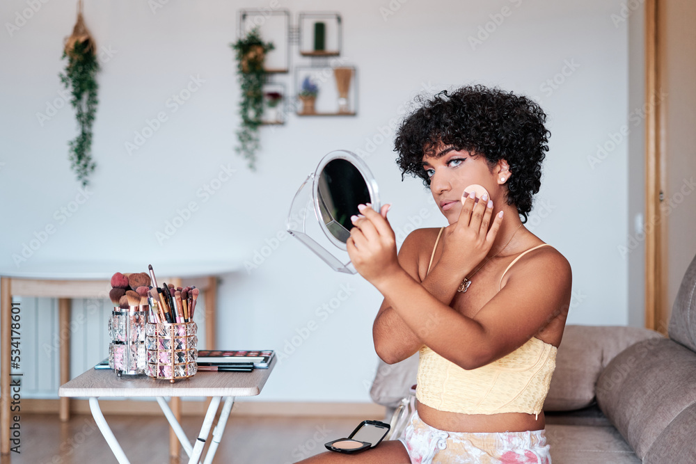 Transgender woman applying compact powder on her face while doing her ...