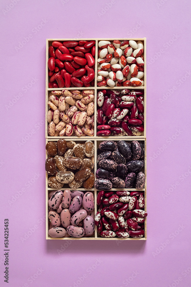 Two sets of organic beans in a wooden boxes on a pink background ...