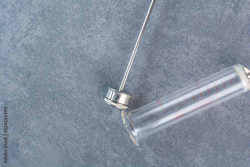 Parts of metal syringe on marble background Stock Photo | Adobe Stock