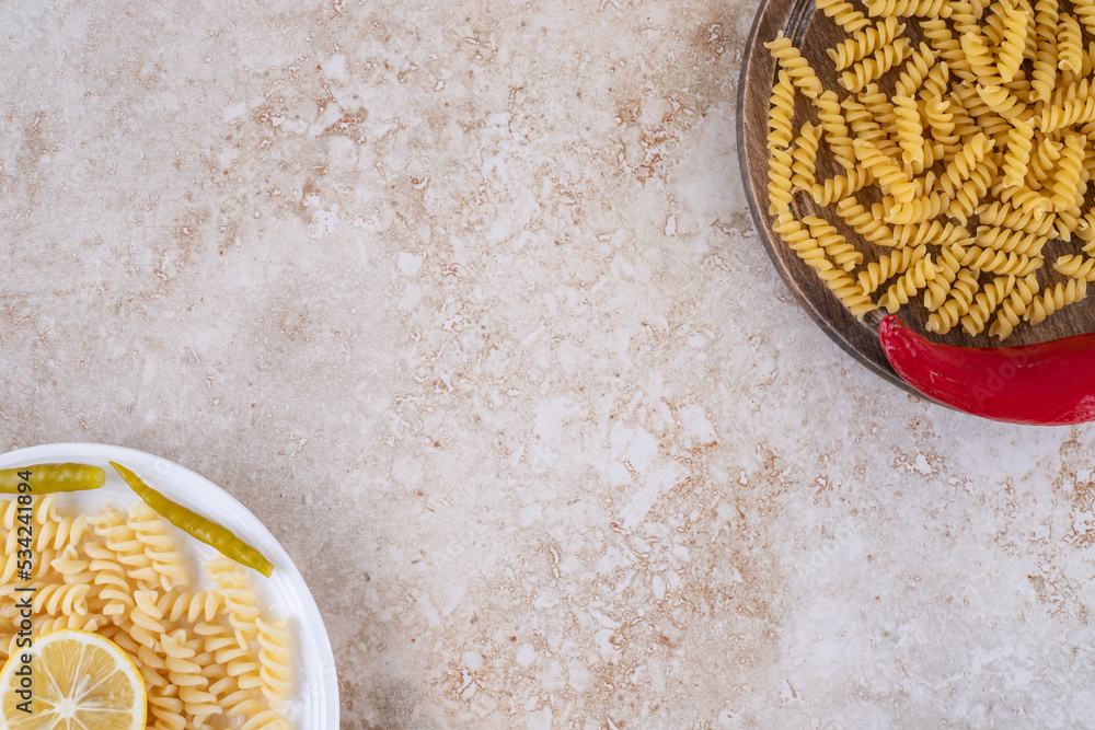 Oppositely aligned portions of pasta in raw and cooked states on marble ...