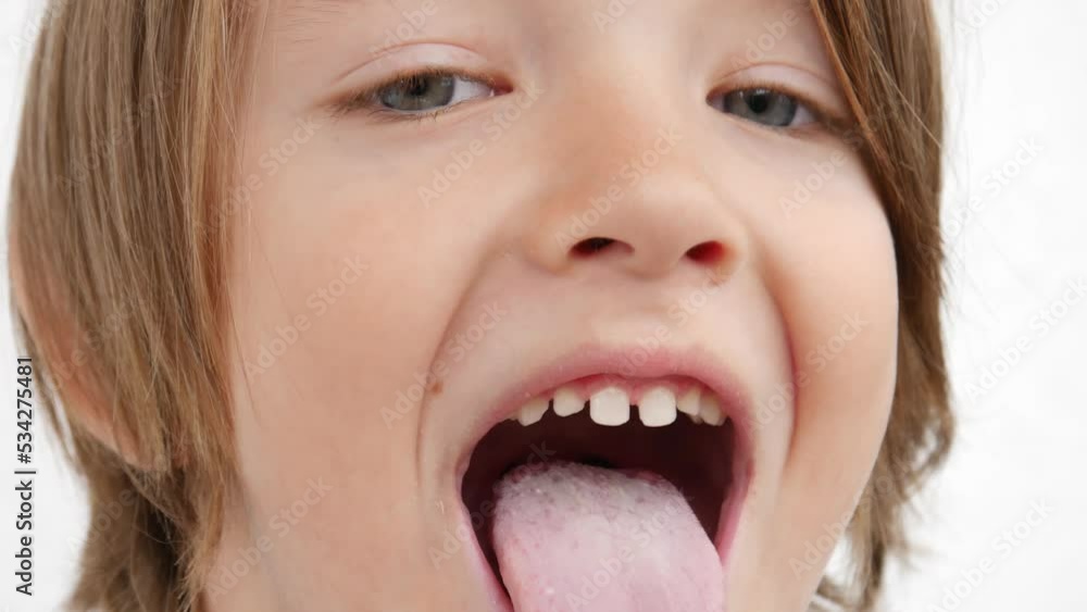 Close-up of the face of a happy cute boy opening his mouth and sticking ...