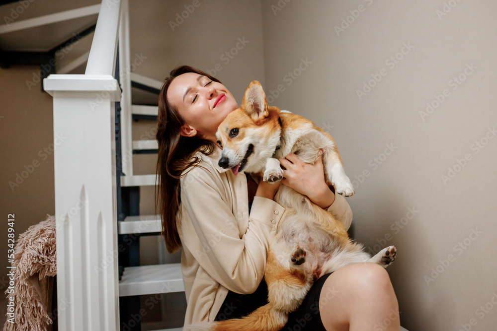 Attractive girl hug and play with corgi dog at home. Welsh Corgi ...