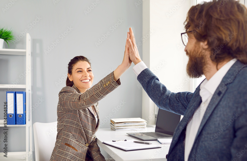 Joyful positive colleagues in office give each other high five after ...
