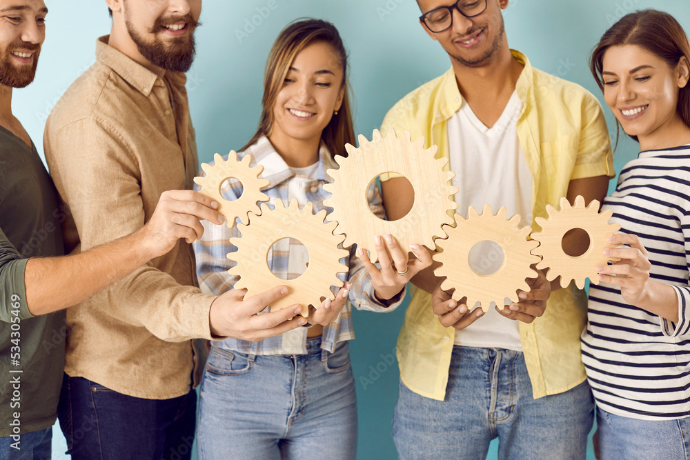 Team of happy young multiethnic people joining cog wheels. Group of ...