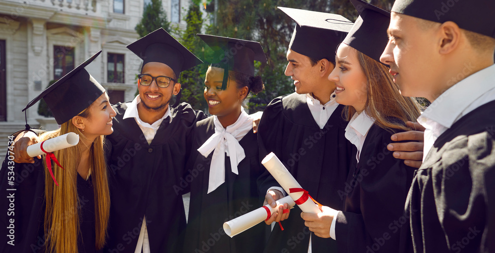 Group of multicultural smiling people in graduation wear talking ...