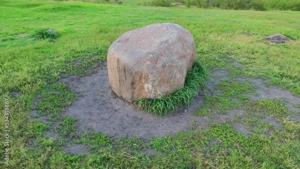 One large ritual stone lies on the ground. Green grass. Pagan ancient ...