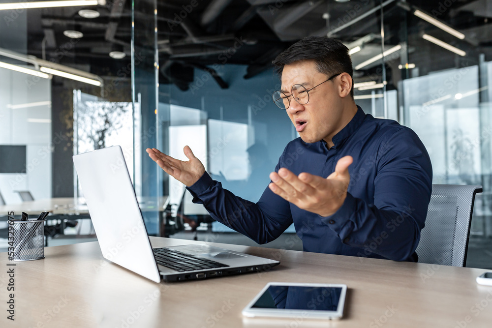Frustrated and angry asian boss yelling at laptop, failure man working ...