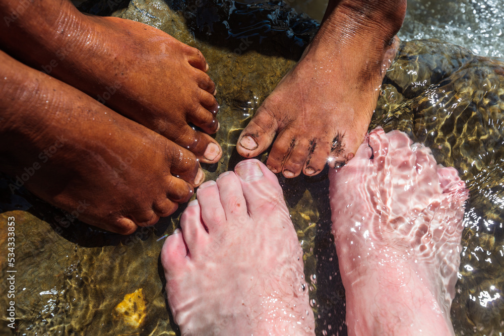 Western tourist trekker washing feet in a clear water stream, with ...
