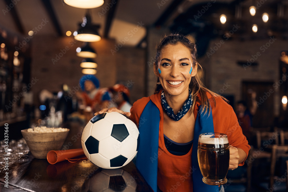Happy female soccer fan drinking beer in pub during world cup and ...