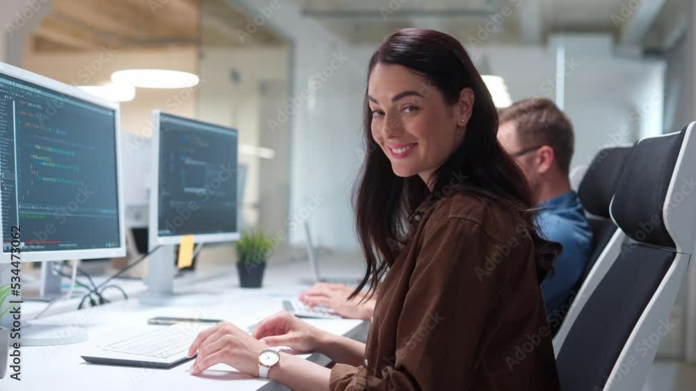 Rear of young pretty woman IT programer working on desktop computers typing on keyboard coding a ...