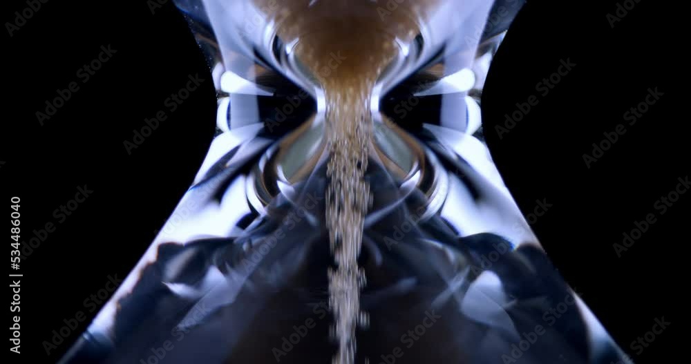 Hourglass. Sands move through hour glass. Sandglass close-up on a black ...