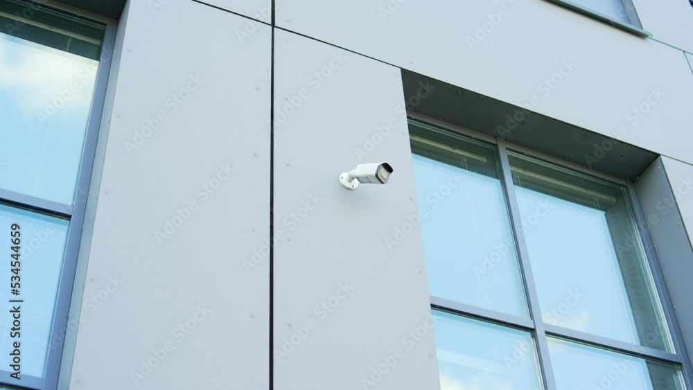 White CCTV security surveillance camera built into the metal wall of ...